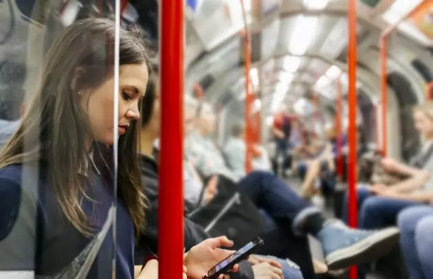 Was ist ein Hypochonder? Großbritannien, London, junge Frau in der U-Bahn mit Blick auf das Handy