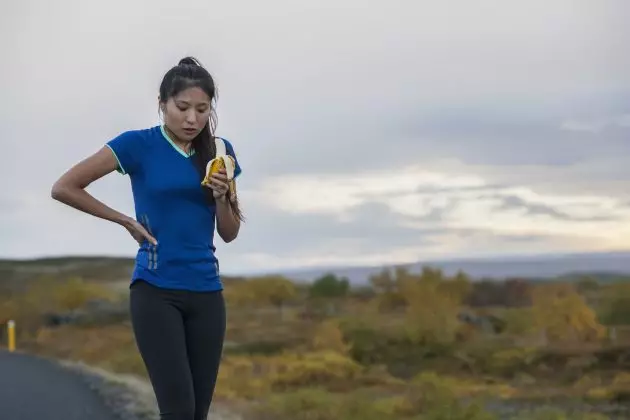 Harjoitusvinkkejä maratoniin: nainen syö banaania treenin aikana Islannin maaseudulla