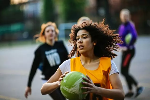 Establecemento de obxectivos: tiro de acción dun xogador de netball atrapando o balón nunha pista deportiva ao aire libre