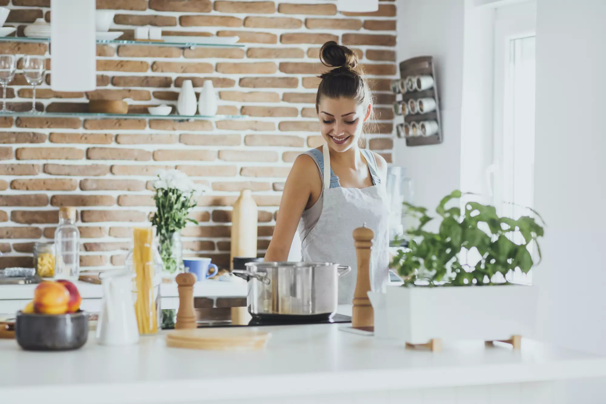 持続可能な食事：コンロに鍋を置いて料理をしているキッチンの女性