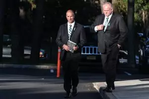 El padrastro de Gabby, Jim Schmidt (izquierda), visto con una cinta verde azulado en su funeral