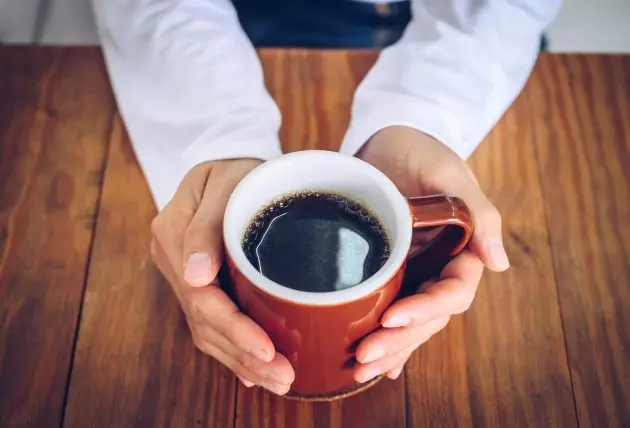 Types de maux de tête : quelqu'un tient une tasse de café noir avant de boire