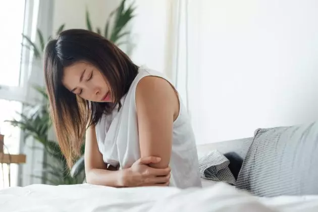 질 감염 유형: 침대에서 위장을 앓고 있는 젊은 여성